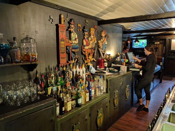 The bar area showcases decades of collected character, with bottles gleaming like jewels against the rustic wooden backdrop.