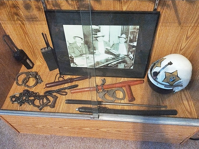 Handcuffs, batons, and vintage police equipment rest in a display case, tools of the trade that haven't changed as much as we might think.