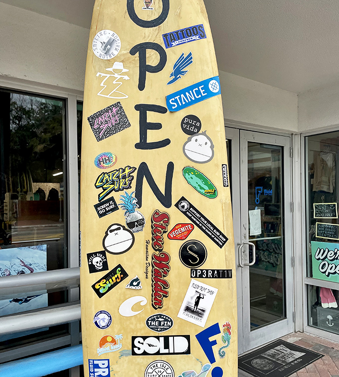 This isn't just a surfboard, it's a sticker-covered diary of beach culture, where every logo tells a story of waves caught and adventures had.