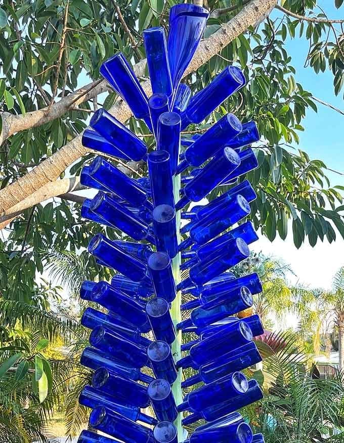 This cobalt bottle tree captures both sunlight and imagination, turning discarded glass into a sculptural masterpiece that glows from within.