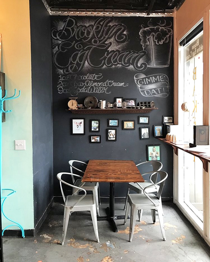 A cozy corner with chalkboard art announces "Brooklyn Egg Cream" &ndash; ironically containing neither egg nor cream but 100% delicious.