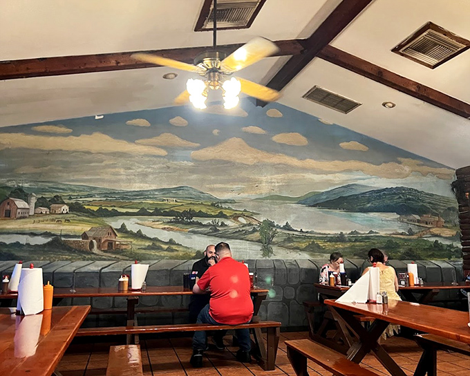The dining room's landscape mural creates a pastoral backdrop for the serious business of barbecue appreciation, making every meal feel like a countryside retreat.