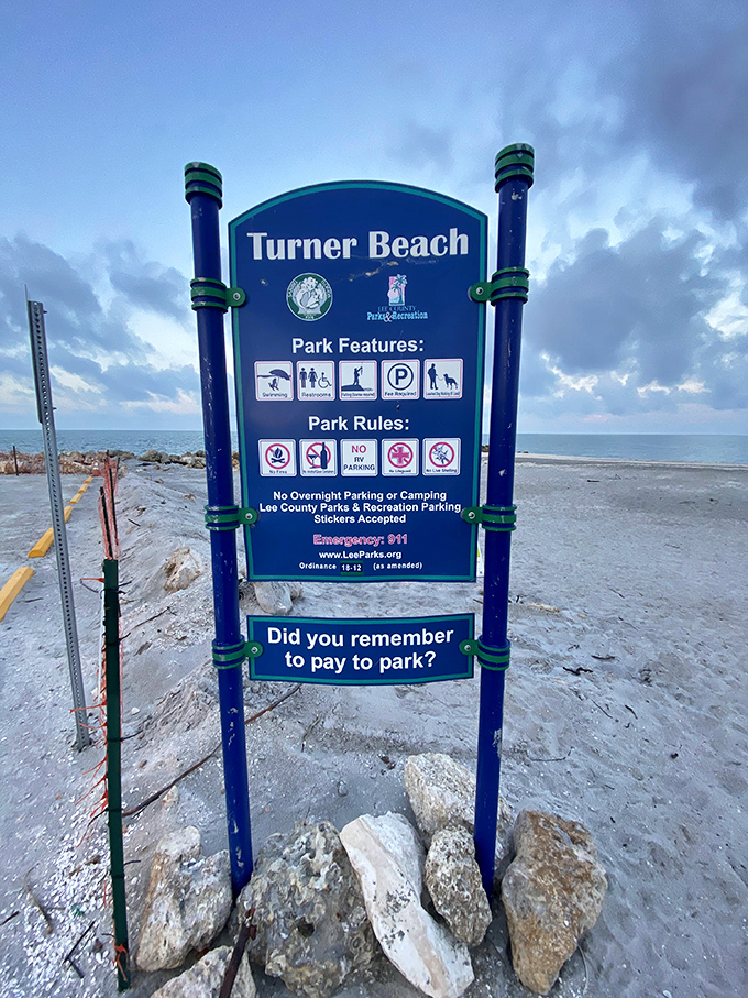 The beach's information sign reminds visitors of park rules while the Gulf of Mexico stretches endlessly behind it.