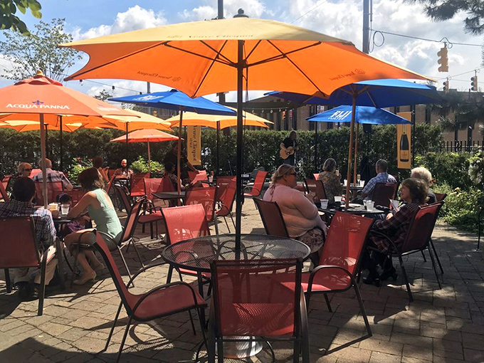 Vibrant orange umbrellas dot the garden patio, creating a cheerful oasis for alfresco dining against the mansion's impressive fa&ccedil;ade.