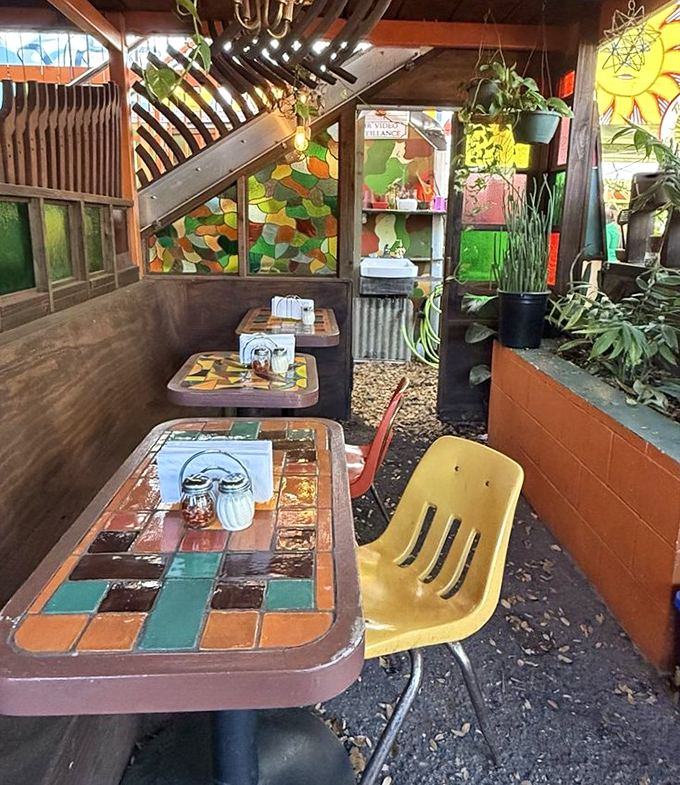 A secret garden of pizza contemplation where stained glass catches the light and plants create a greenhouse vibe for outdoor dining.