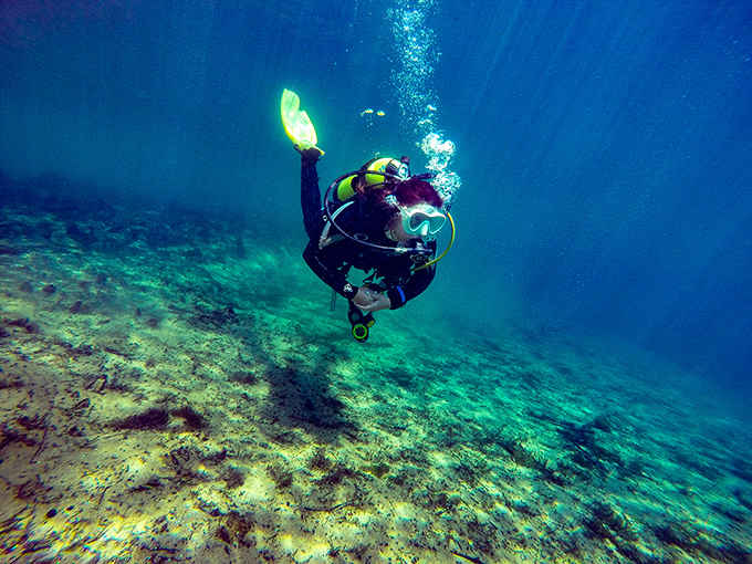 Scuba divers explore underwater caverns that feel like nature's own cathedral, where limestone formations create an otherworldly landscape of beauty.