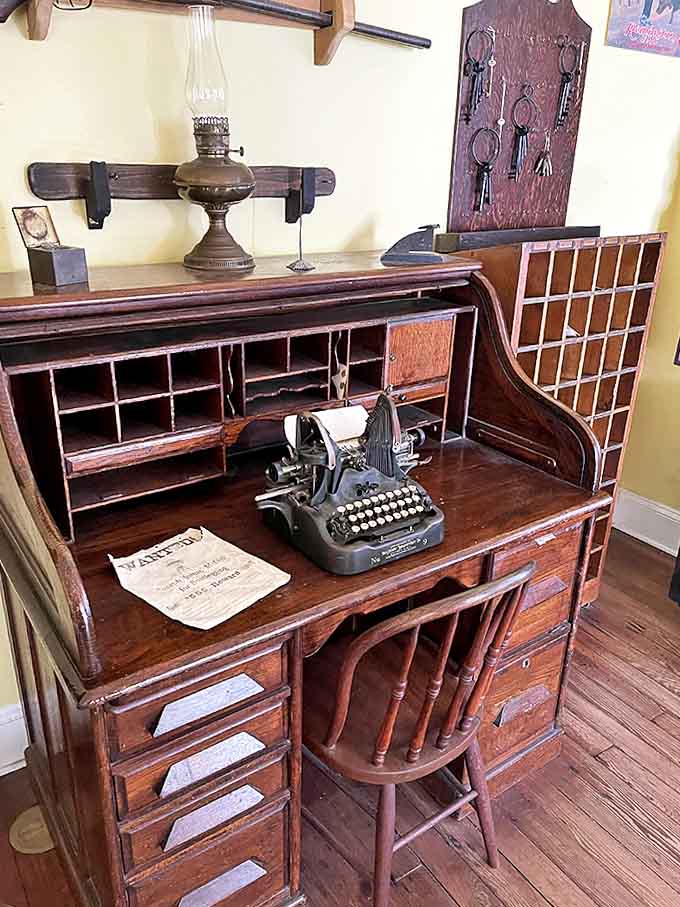 An antique roll-top desk with vintage typewriter showcases the administrative side of justice, where countless prisoner records were once maintained.