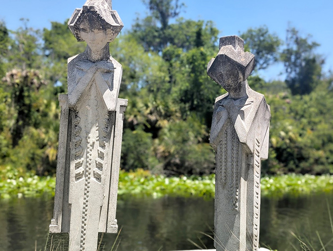 Concrete Statues: Silent sentinels standing watch over the water, their weathered forms blending art and memorial in the distinctive cemetery style of yesteryear.