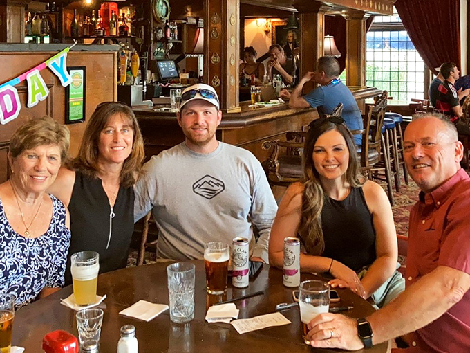 Happy patrons raising glasses in the universal pub language of good cheer &ndash; ghost stories improve with each round.