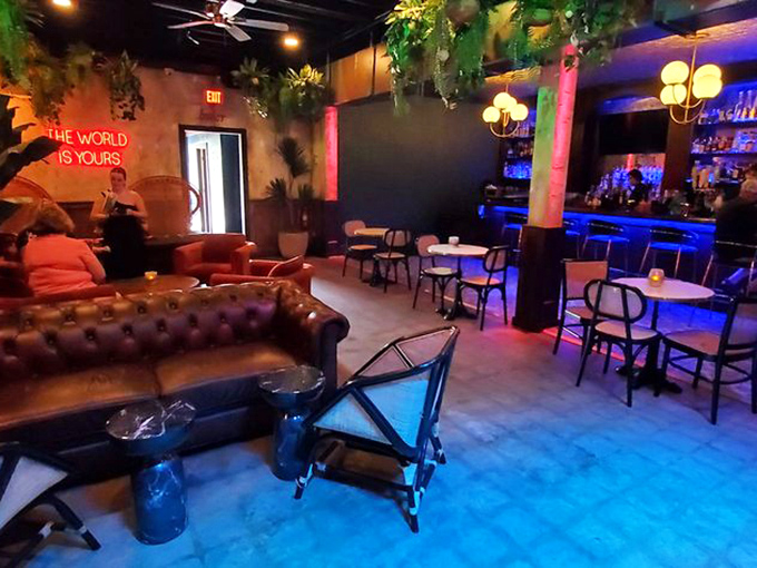 Lush plants cascade from above while a neon sign reminds patrons that "The World Is Yours" in this cozy corner of the secret bar.