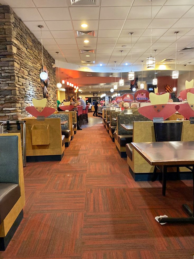 The dining area stretches invitingly with warm wood tones and stone accents, each booth a private island in a sea of delicious possibilities.
