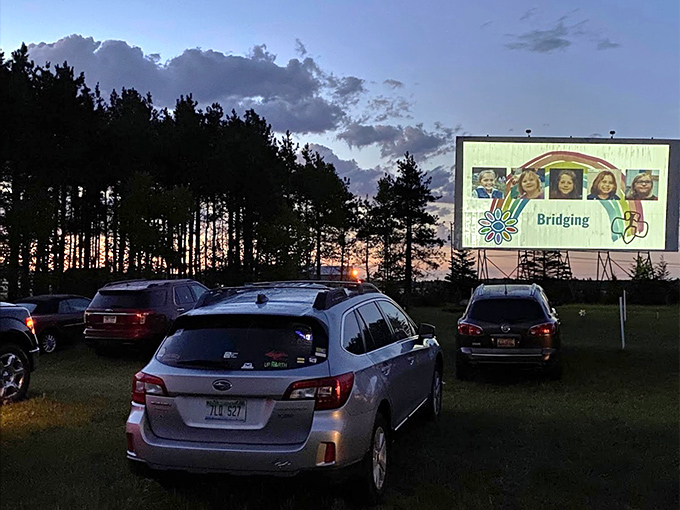 "Bridging" plays on the massive screen as twilight deepens, cars positioned like an audience of metal whales at attention.