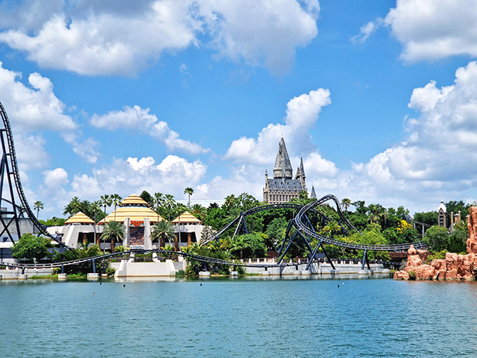 Peaceful waters reflect roller coaster chaos above &ndash; nature and engineering in perfect theme park harmony under Florida's impossibly blue skies.