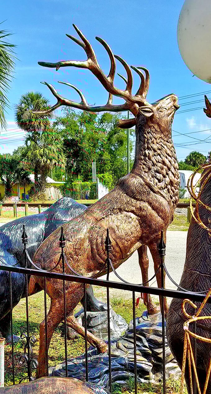 A majestic stag with impressive antlers stands alert, its detailed bronze finish catching the sunlight beautifully.