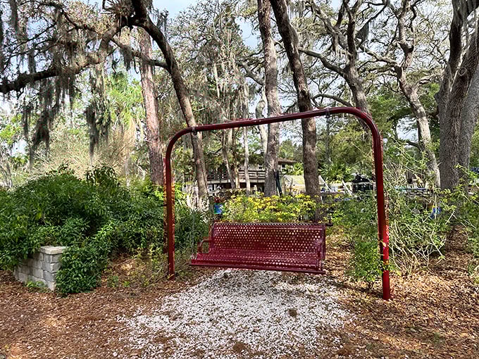 This cherry-red swing bench practically begs visitors to pause, sway gently, and absorb the tranquility of the surrounding nature.
