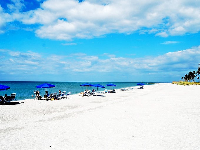 South Seas Resort's beach stretches toward the horizon, where blue umbrellas mark civilization's gentle footprint on this natural paradise.