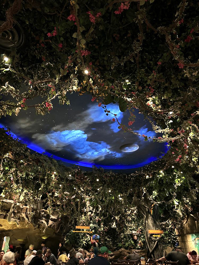 Look up to see a magical ceiling where artificial stars twinkle through lush foliage, creating a nighttime jungle canopy above diners.