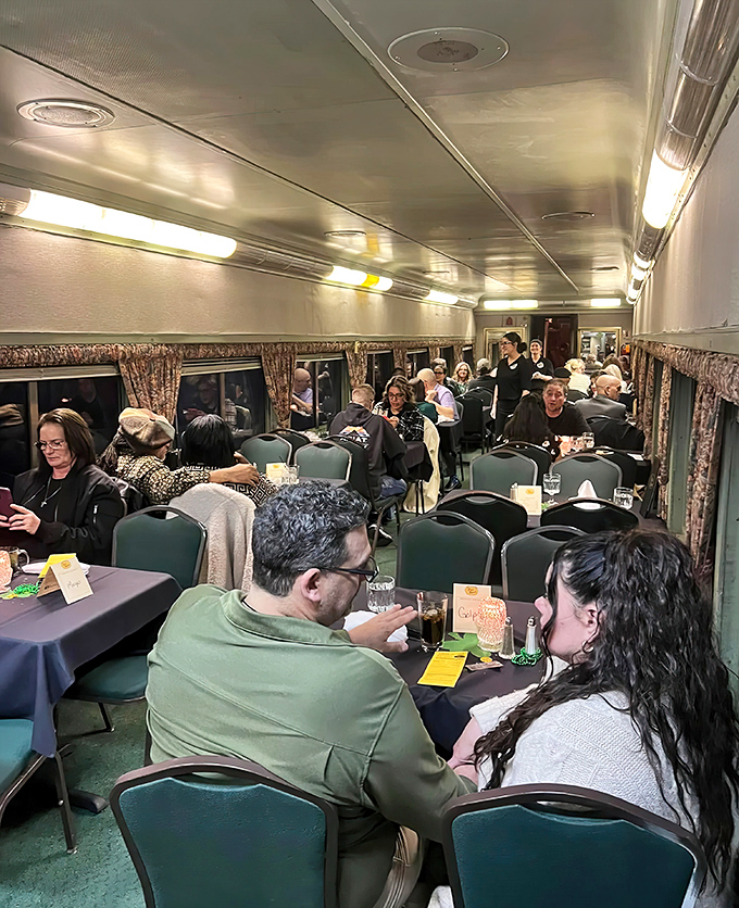 Passengers engage in the interactive experience, some leaning in to catch every word while others eye fellow diners with good-natured suspicion.
