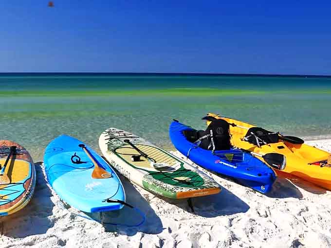 Colorful kayaks and paddleboards wait at the water's edge, promising adventures on Grayton's crystal-clear waters.