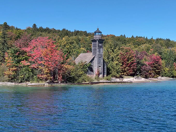 This weathered lighthouse stands guard amid autumn's fiery display, a stalwart sentinel that has guided generations through Superior's moody waters.