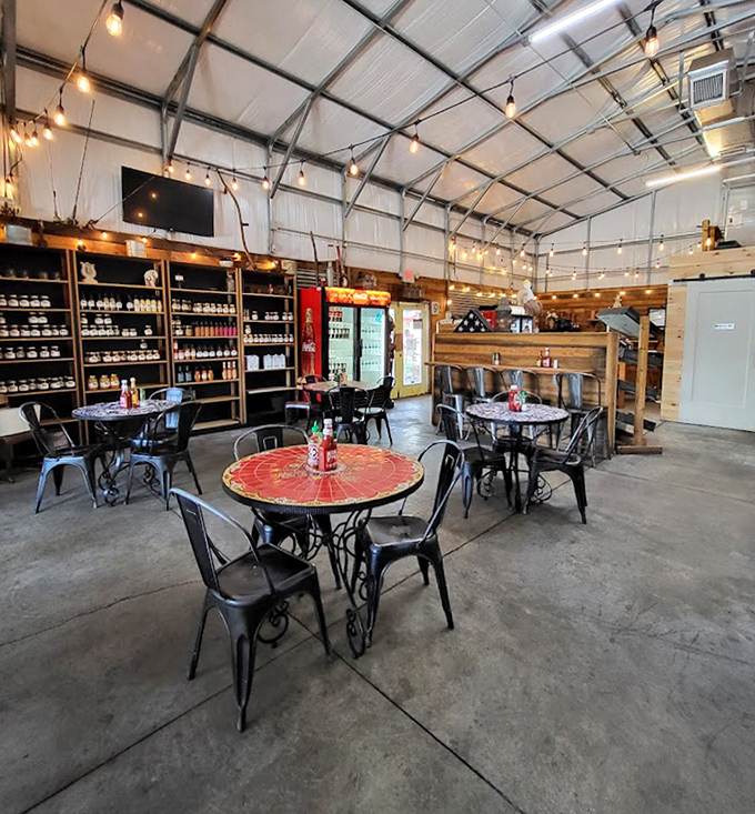 String lights cast a warm glow over the industrial-chic interior, where colorful tables add pops of personality to the rustic space.