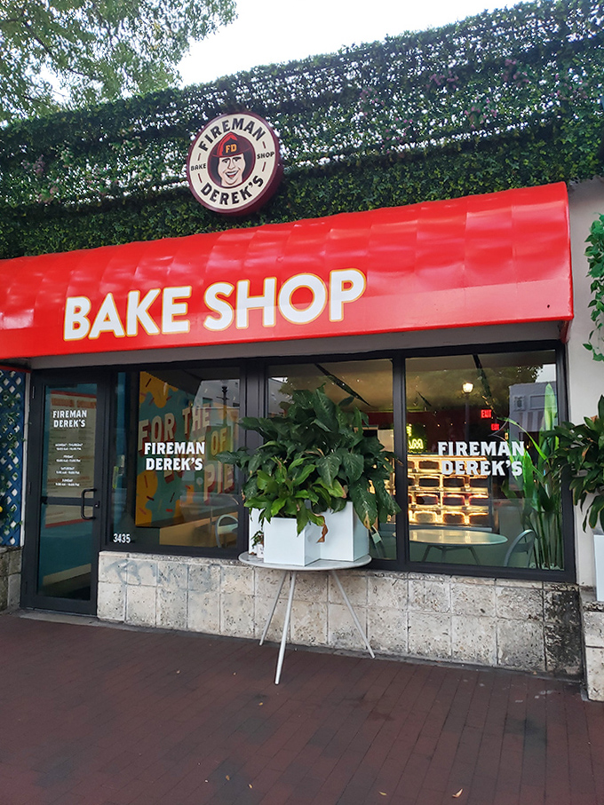 The welcoming facade of Fireman Derek's, where the bright red awning and leafy surroundings create an inviting dessert oasis.