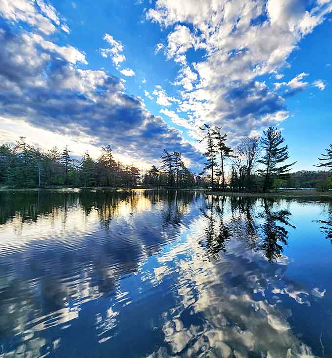 Clouds reflect perfectly in still waters, creating a double sky that makes you question which way is up.