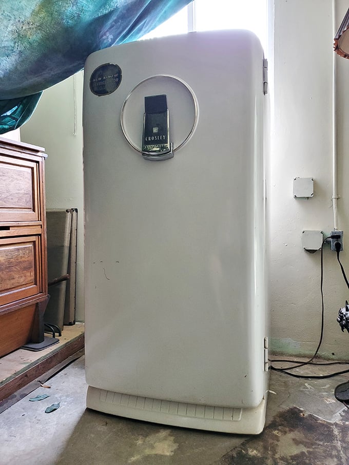 That vintage Crosley refrigerator stands guard like a faithful appliance soldier, long past its cooling days but still reporting for duty.