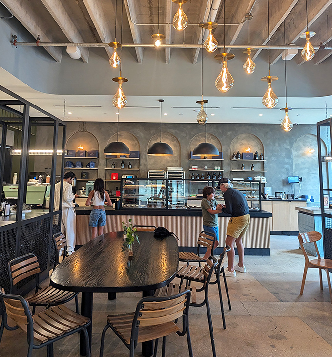 Another Interior Angle: Industrial chic meets cozy comfort under soaring ceilings where vintage-inspired lighting casts a golden glow on happy faces.