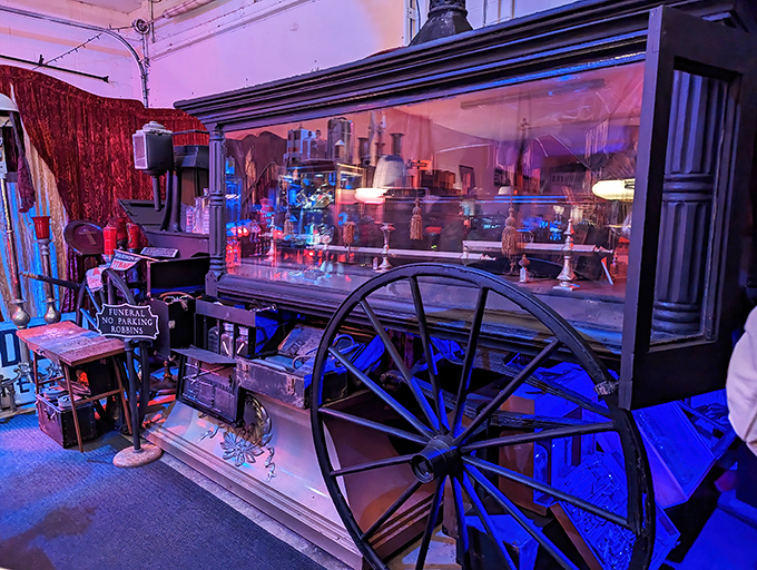 A vintage funeral carriage gleams under dramatic lighting, transporting visitors back to an era when death rituals were elaborate public affairs.