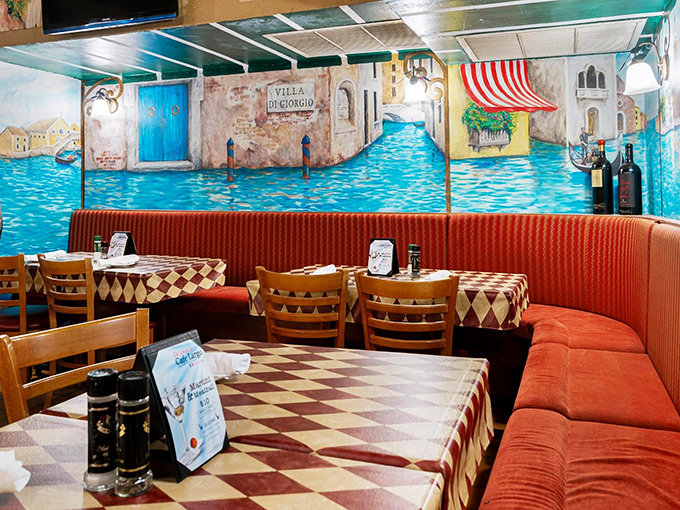 Cozy booths with Venetian canal murals offer intimate dining spaces where conversations flow as freely as the wine.