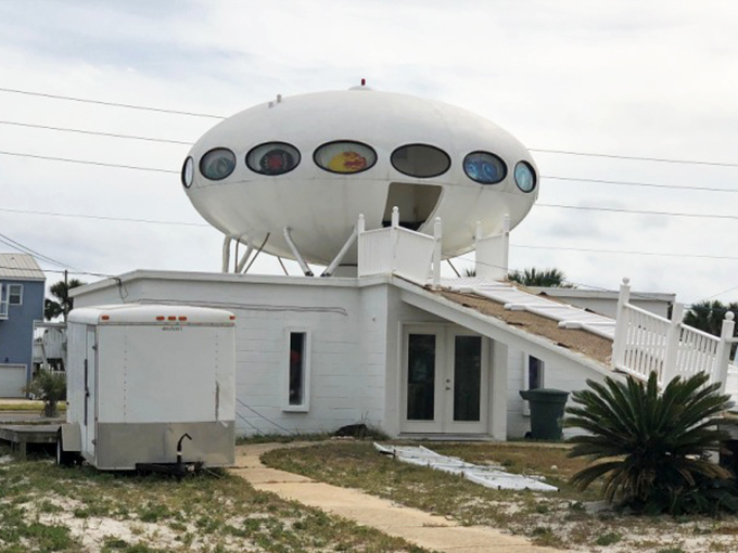 The distinctive oval portholes and supporting legs give this Futuro its unmistakable flying saucer silhouette against the coastal landscape.