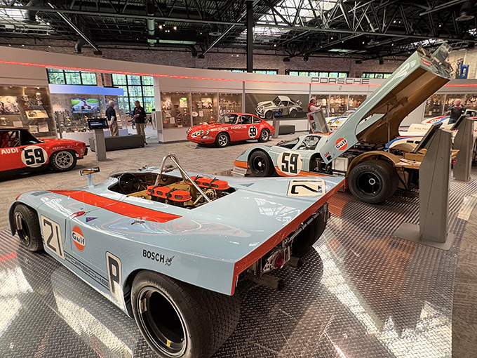 Gulf Racing Porsches cluster together like they're sharing war stories from Le Mans, their battle-tested bodies still wearing their colors with unmistakable pride and style.