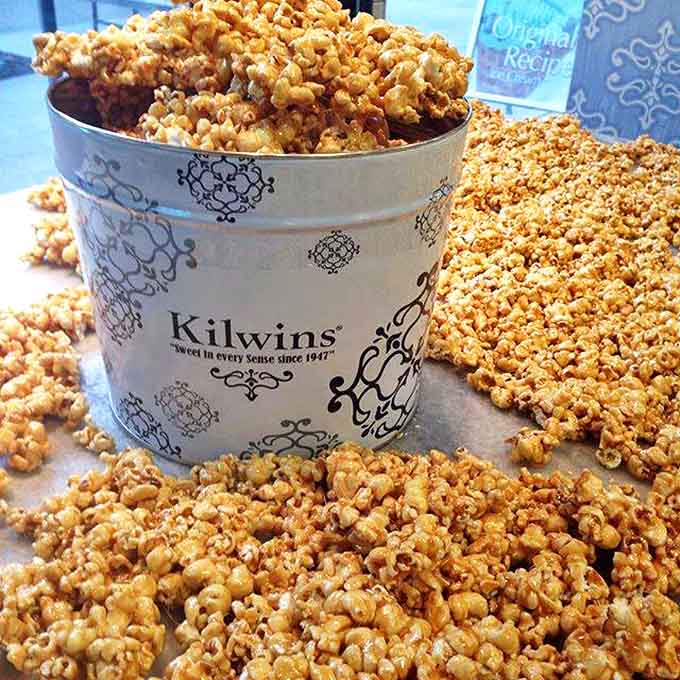 Golden caramel popcorn overflowing its container – crunchy, sweet clusters that make regular popcorn seem like a sad, distant relative.