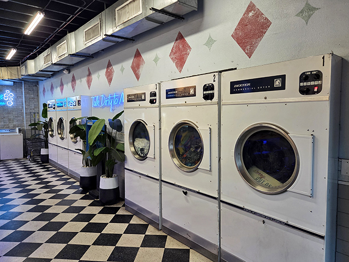 Functioning vintage washing machines line the wall beneath retro diamond patterns, completing the immersive laundromat theme with impressive commitment to the bit.