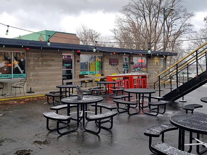 Metal tables stand ready for strategic gaming discussions and victory celebrations under strings of lights that twinkle like distant starfields.