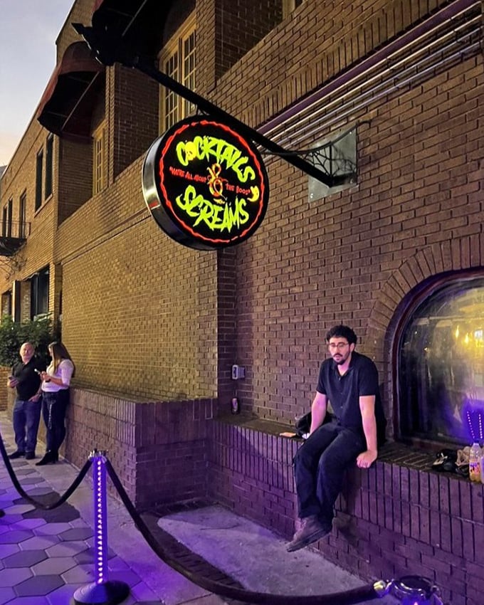 The entrance to Cocktails & Screams beckons with its glowing sign, promising a night of delightful darkness in downtown Orlando.