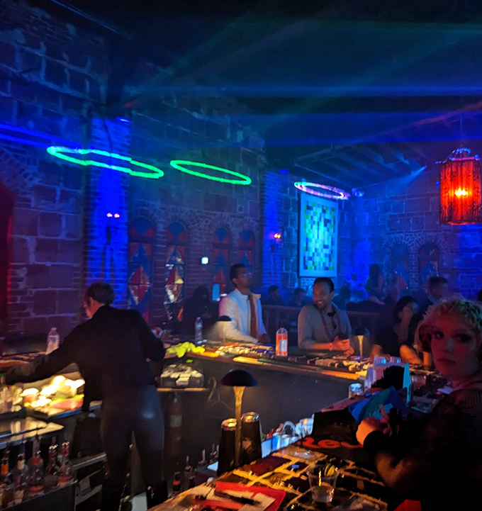 DJs work their magic behind illuminated equipment, curating soundscapes that guide the night's energy while colorful lights transform the space around them.