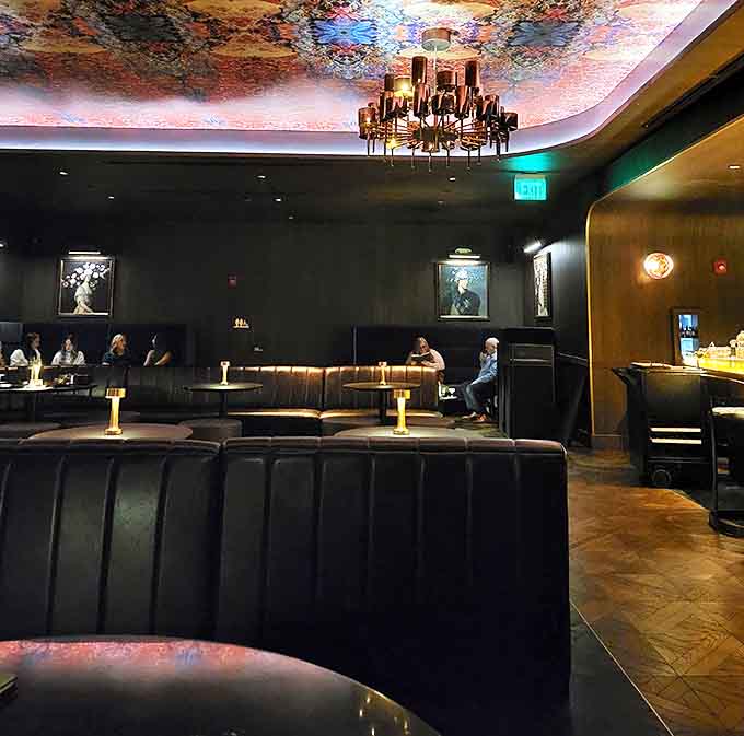 Dark walls, plush seating, and that mesmerizing ceiling create an atmosphere that's equal parts sophisticated and slightly mysterious.