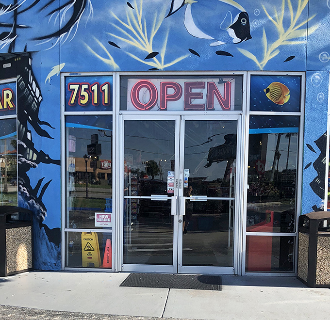 Welcoming entrance: The "OPEN" sign glows like a beacon against the underwater mural backdrop, inviting tourists to dive into this ocean of licensed merchandise.