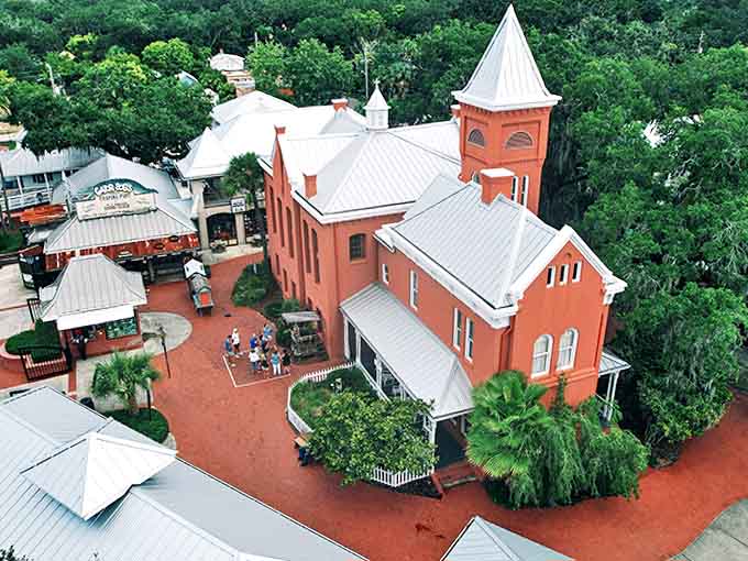 An aerial view reveals the Old Jail Museum complex in all its historic glory, nestled among St. Augustine's lush landscape like a coral-colored time capsule.