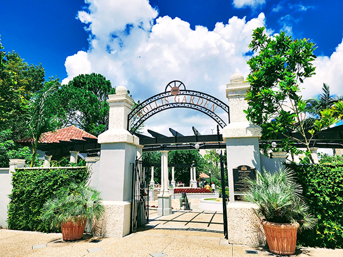The garden entrance stands as a promise of wonders within, its wrought iron gate and stone pillars marking the threshold between ordinary and extraordinary.