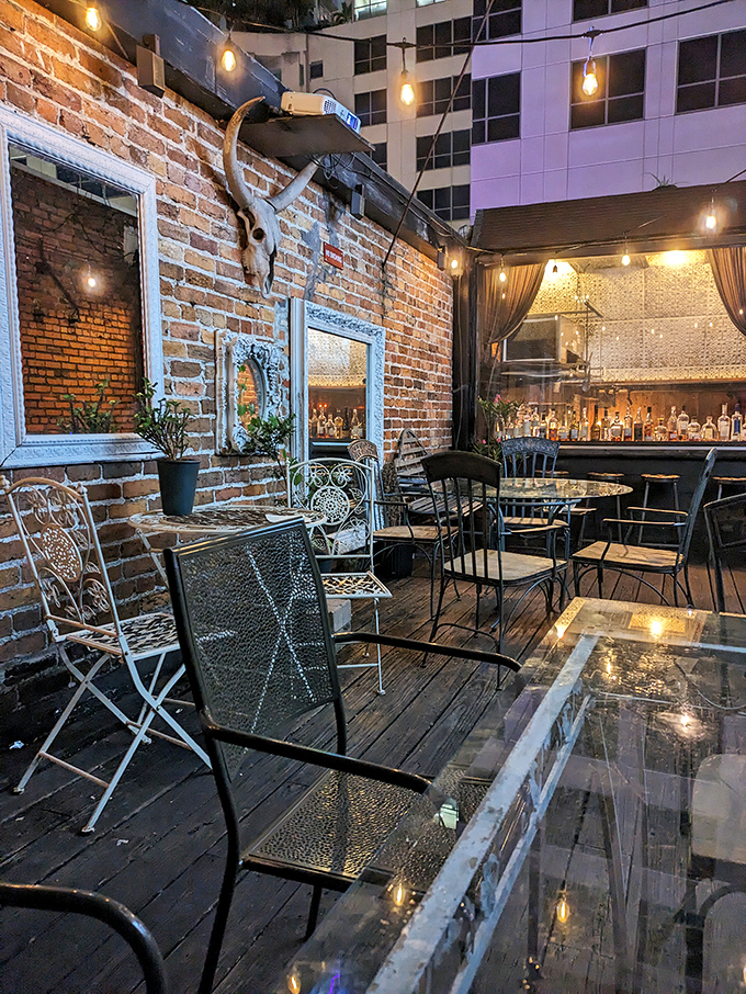 Outdoor seating: String lights illuminate the secret patio where wrought iron furniture and exposed brick create an al fresco extension of the speakeasy magic.