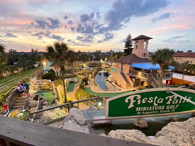 Sunset Golf View: As day fades to dusk, the course transforms &ndash; golden light bathes colorful buildings while strategically placed lighting begins to illuminate the tropical fantasy.