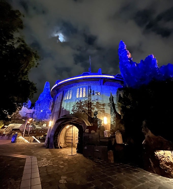 As night falls, Dok-Ondar's exterior transforms into a beacon of blue light, drawing curious travelers into its mysterious depths.