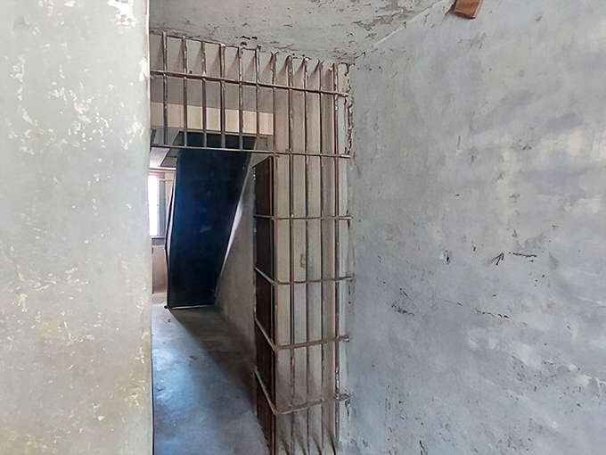 This barred door swings open to reveal that freedom and captivity are sometimes separated by just a few inches of rusted iron.