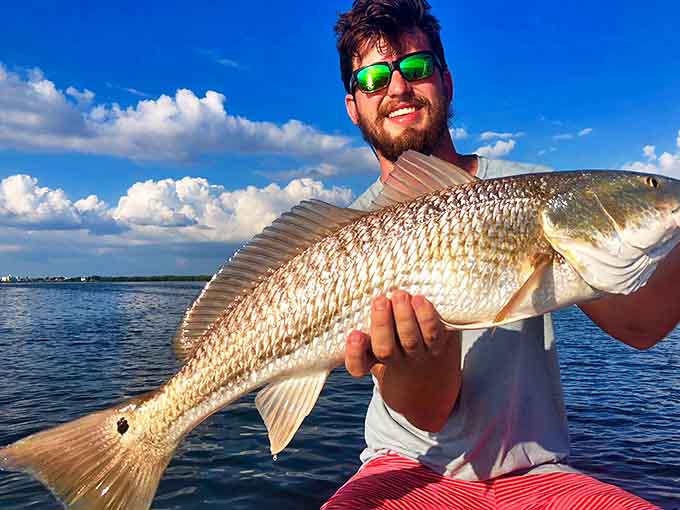A proud angler displays his impressive redfish catch, proof that Egmont Key's waters are as bountiful as they are beautiful.