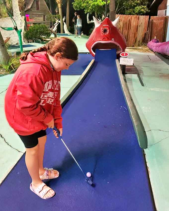 Concentration is key as this young golfer lines up her shot, demonstrating that Goofy Golf's appeal spans generations with its simple, timeless fun.