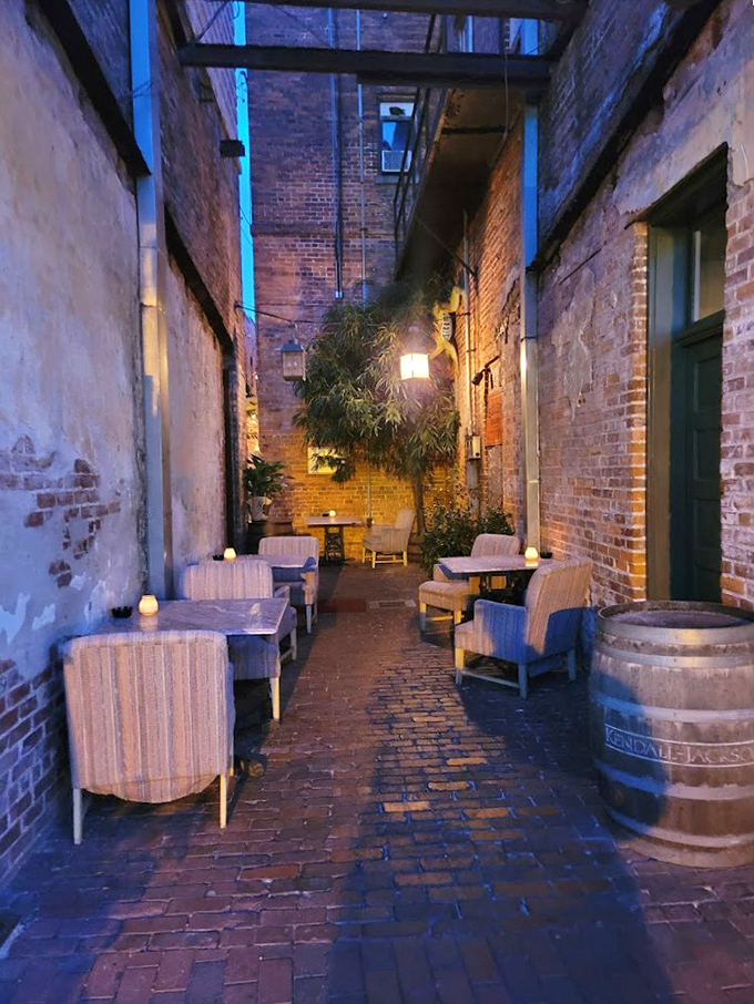 The hidden alleyway seating transforms into an enchanted garden at night &ndash; brick walls whispering stories of celebrations past.