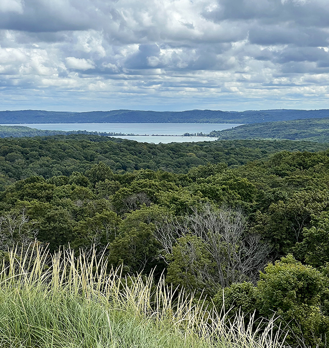 Sprawling green hills meet shimmering waters under dramatic skies&mdash;nature's own masterpiece painting peace across the horizon.
